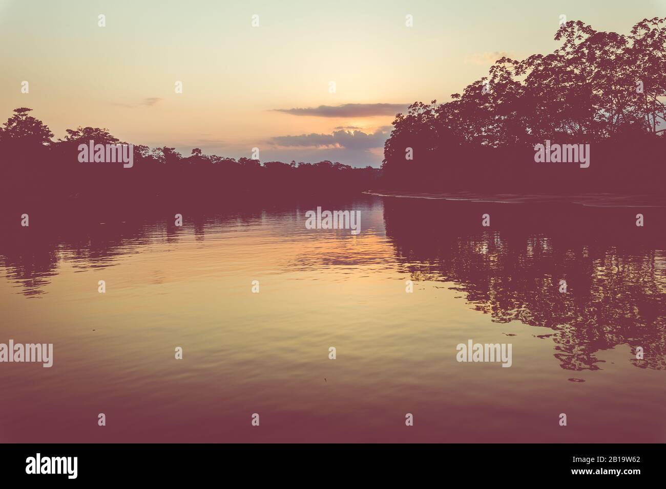 Amazon rainforest sunset during a boat trip with a reflection of the ...