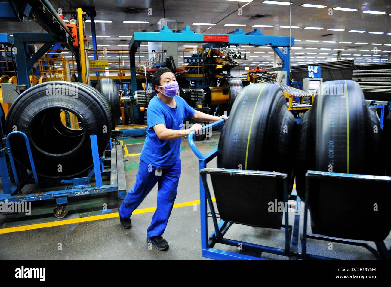 A Chinese worker carts newly-manufactured rubber tires at the plant of ...