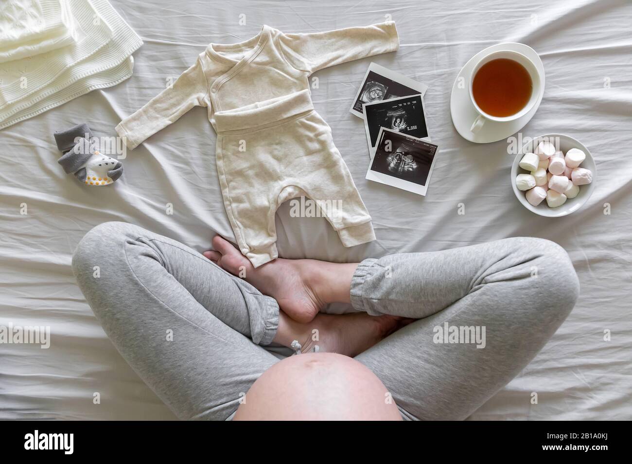 Top view of pregnant woman in the bed preparing baby clothes, pregnancy ...