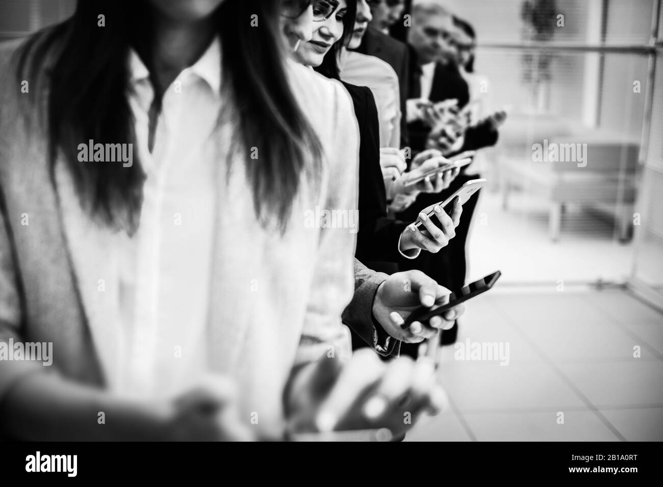 group of young business people looking at their smartphone screens ...