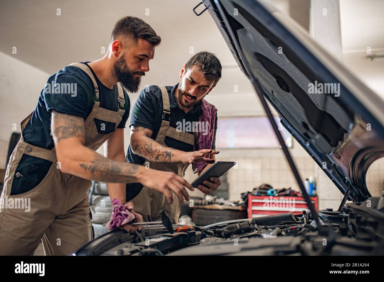 Two mechanics in uniform are working in auto service.Transmission ...