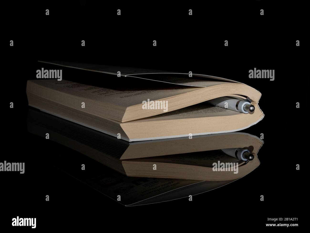 Closed book on black background with mirror reflection. Dramatic side ...