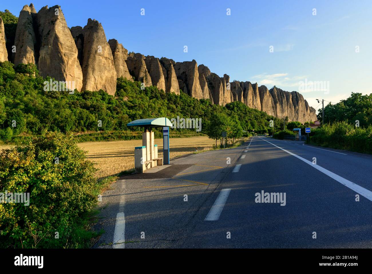 Road with bus stop near famous Penitent rocks illuminated by evening ...