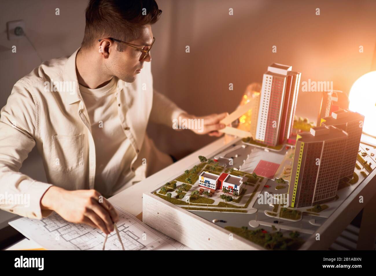 young business man measuring a model of high building, guy wants to ...