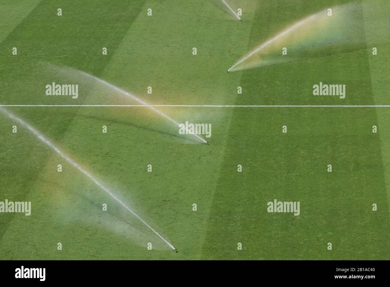 Sprinklers watering a football field before a match with rainbow effect ...