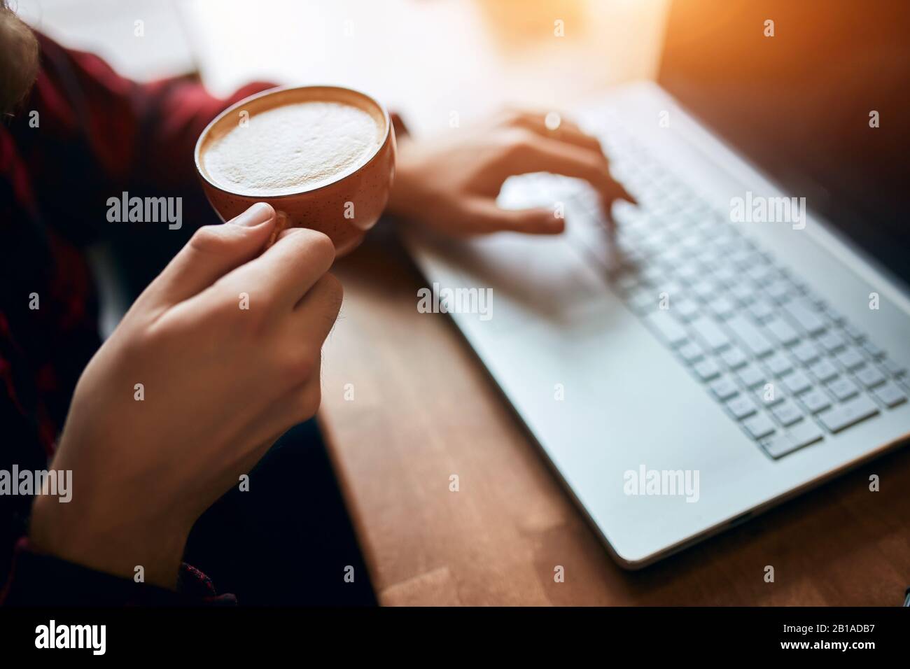 Man in cafe using laptop to chat and play social media and drinking hot ...