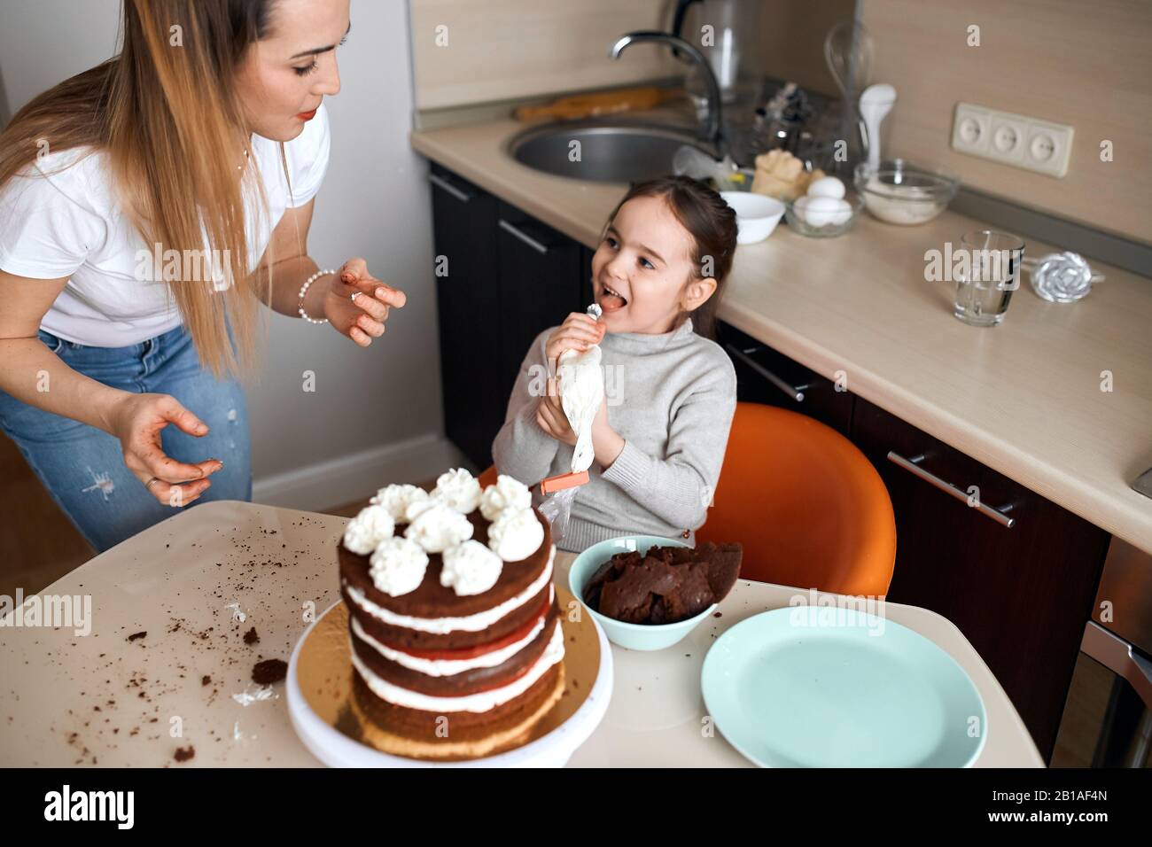 funny little girl squeezing cream into her mouth eating cream while her ...