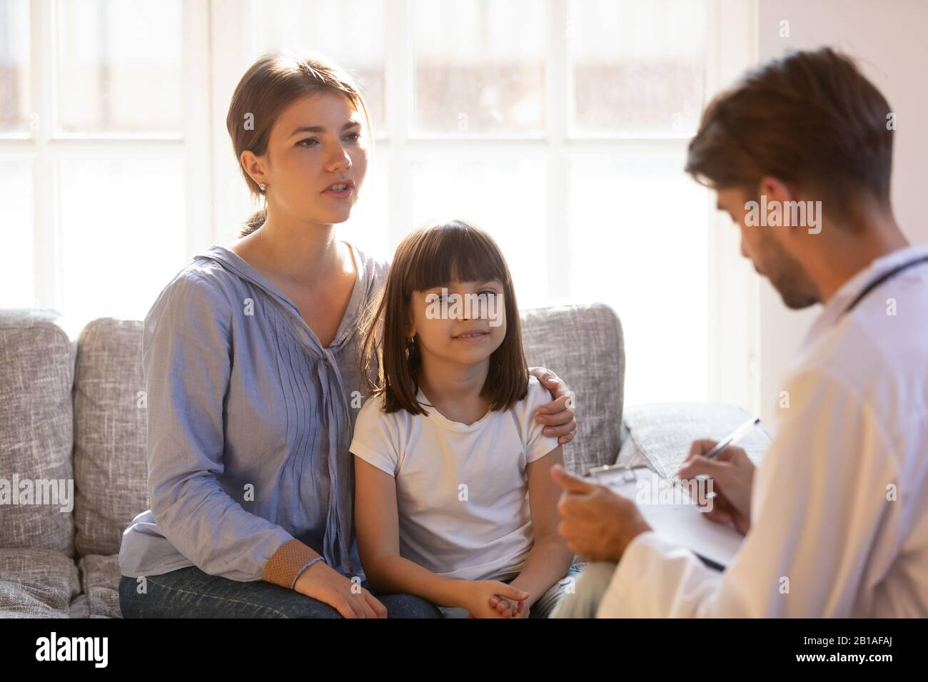 Male doctor visiting mom and daughter at home Stock Photo - Alamy