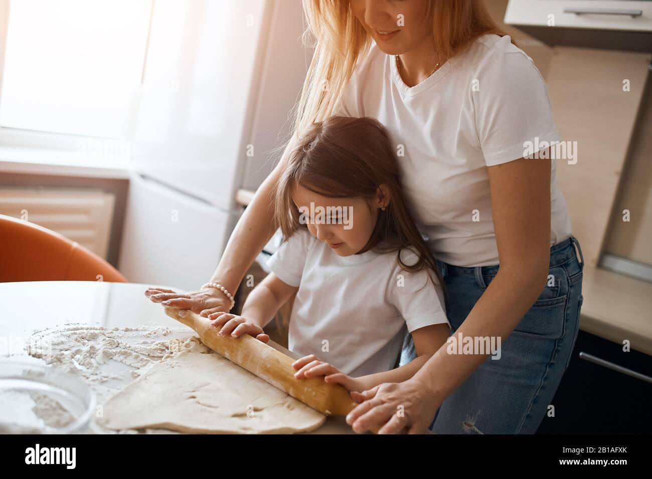 hardworking attractive girl helping her mother to bake a pie for family ...