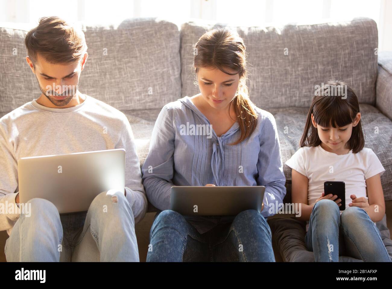 Young family with kid sit using gadgets at home Stock Photo - Alamy