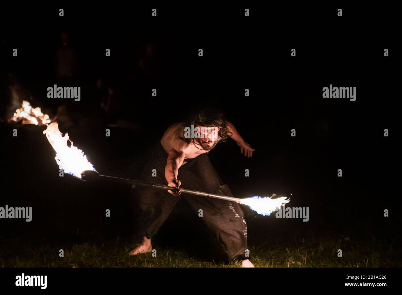 A talented fire dancer is seen using a double ended burning pole during ...