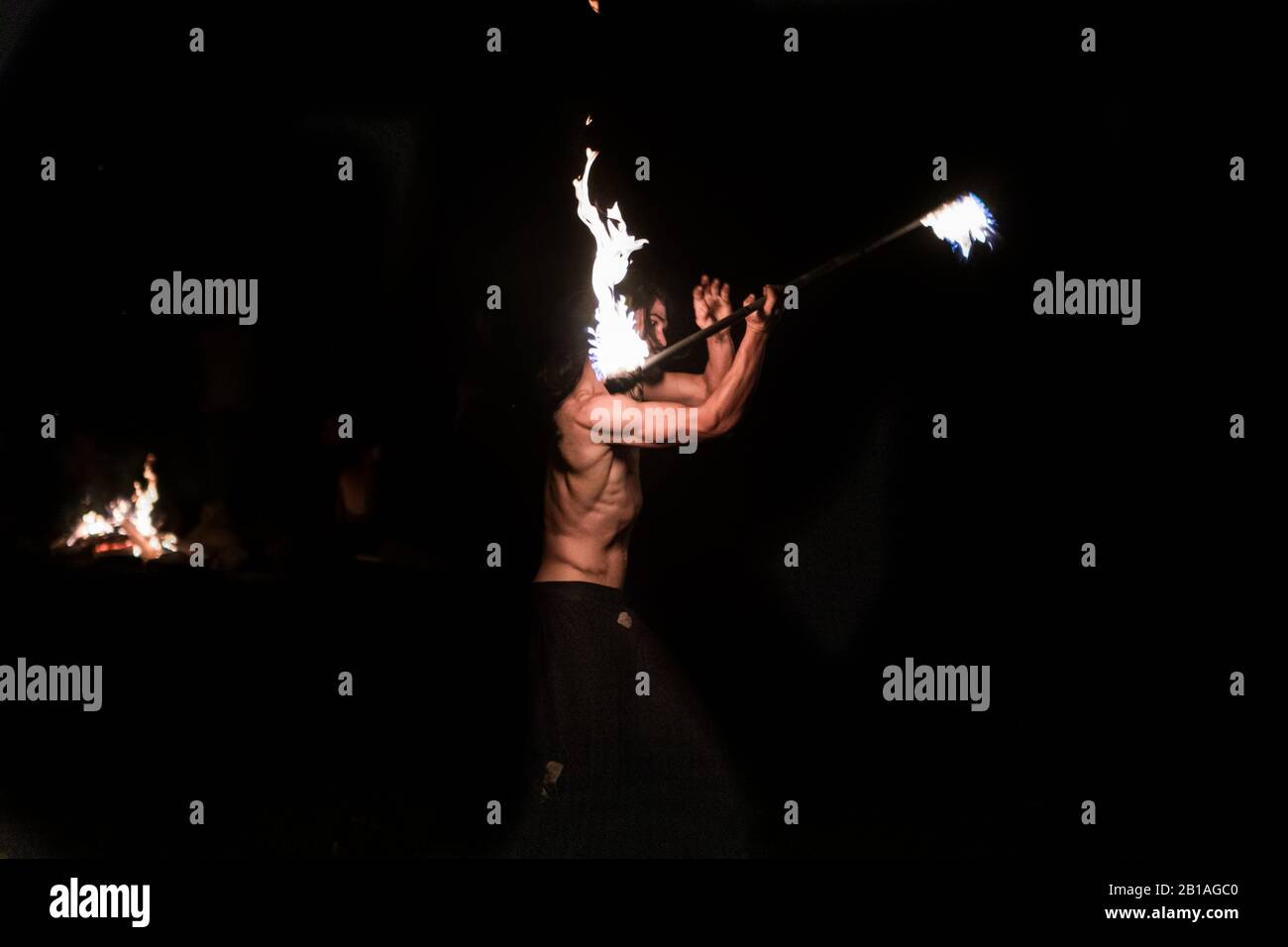 A side profile view with selective focus on a muscular fire dancer ...