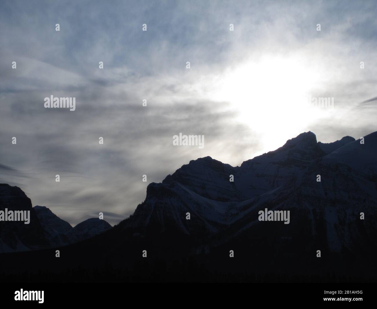 Sun shining through clouds over mountain Stock Photo - Alamy