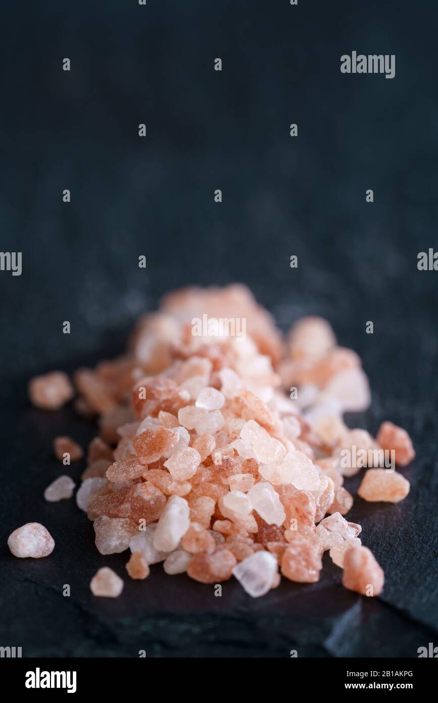 Daily salt intake, 1 teaspoon of pink Himalayan salt. Black background ...