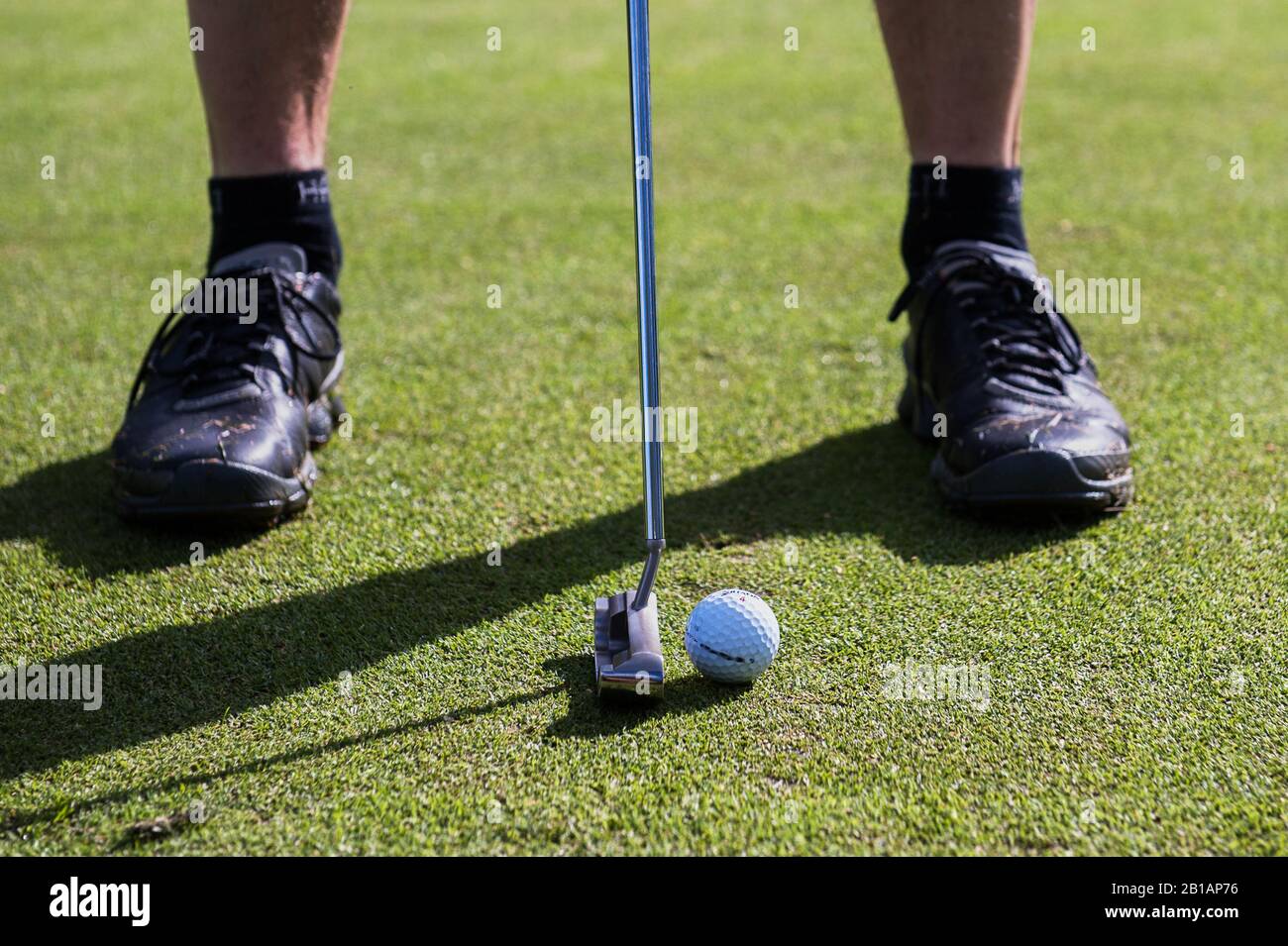 Close-up of golf ball, iron and feet Stock Photo - Alamy