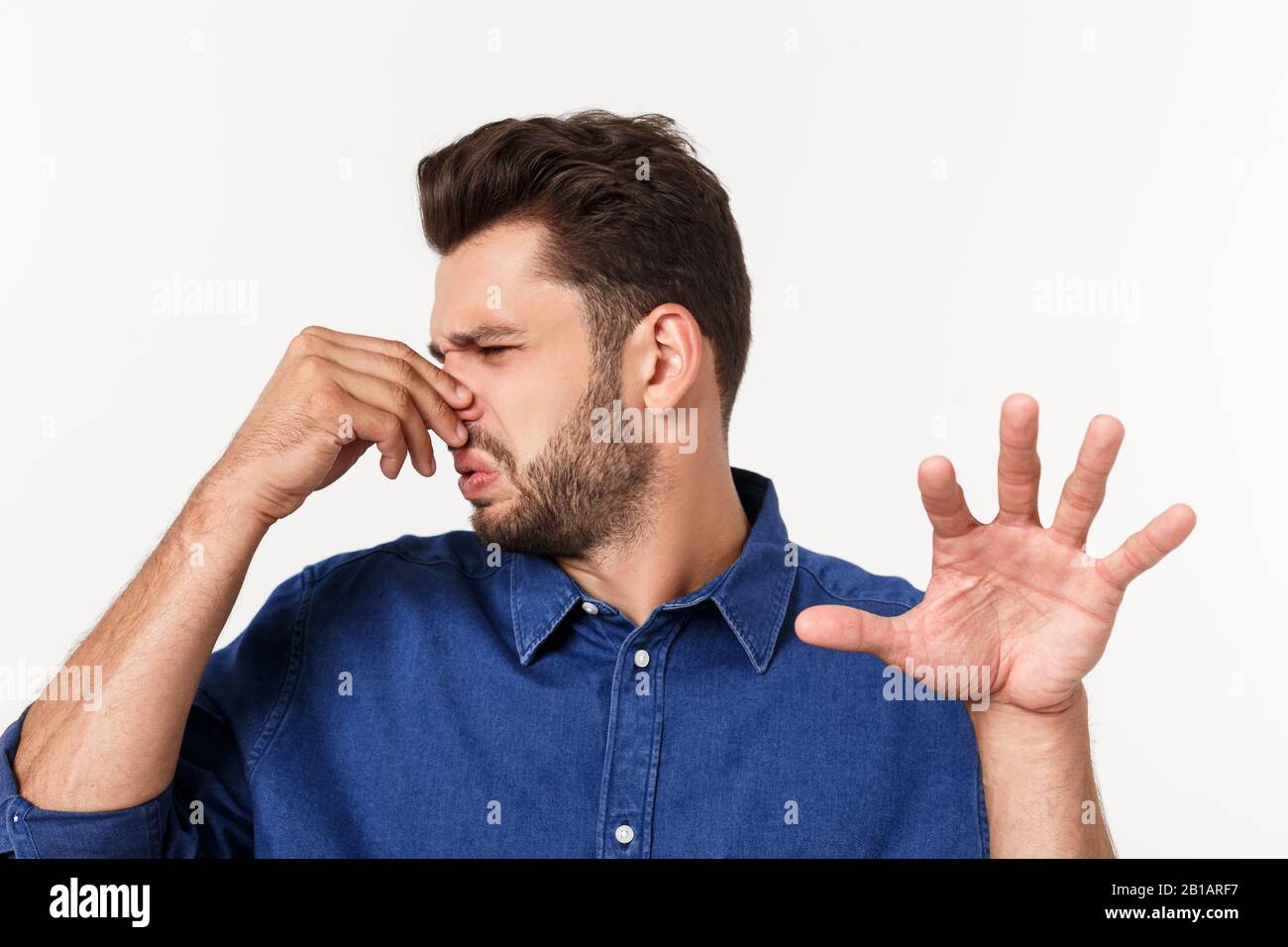 Man holding his nose against a bad smell isolated over grey background ...