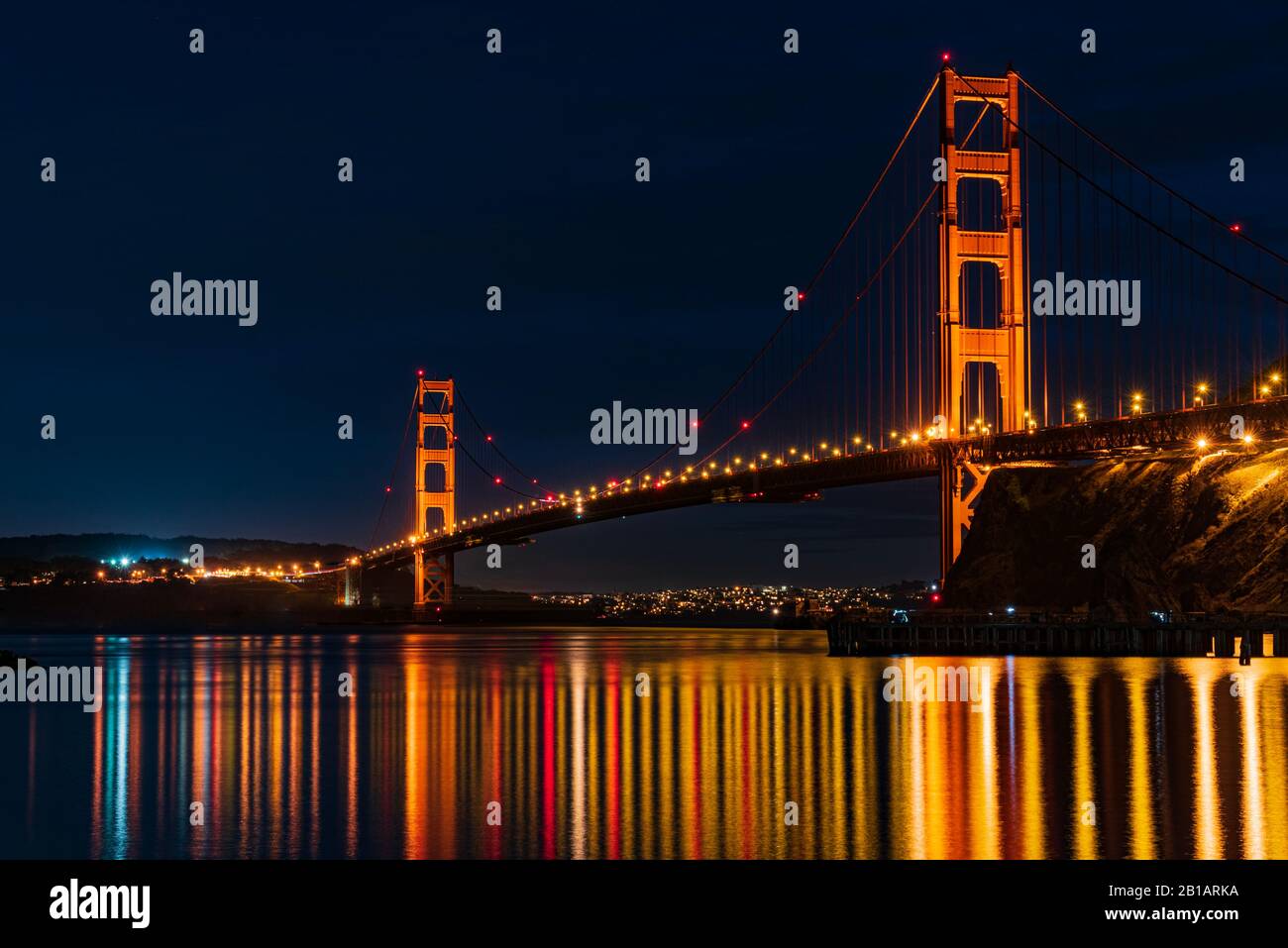 View of the Golden Gate Bridge at night with lights reflections in the ...