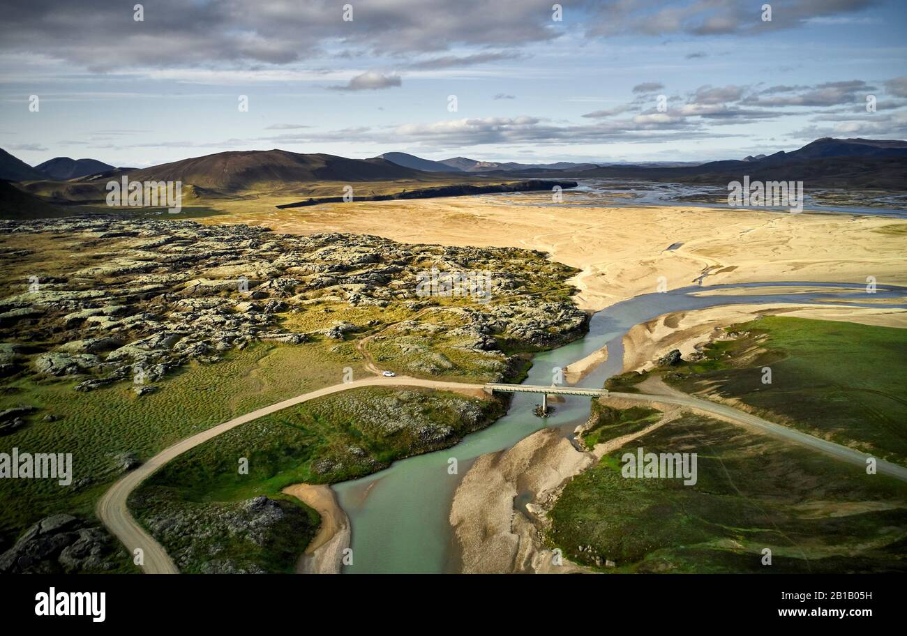 Aerial view of bridge connecting roads over peaceful river in rough ...