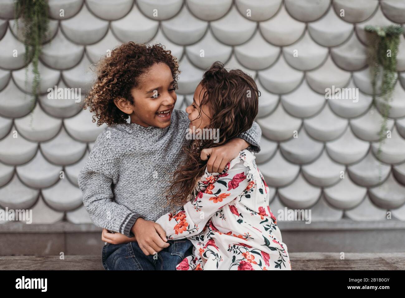 Cute siblings smiling and laughing at each other while hugging outside ...