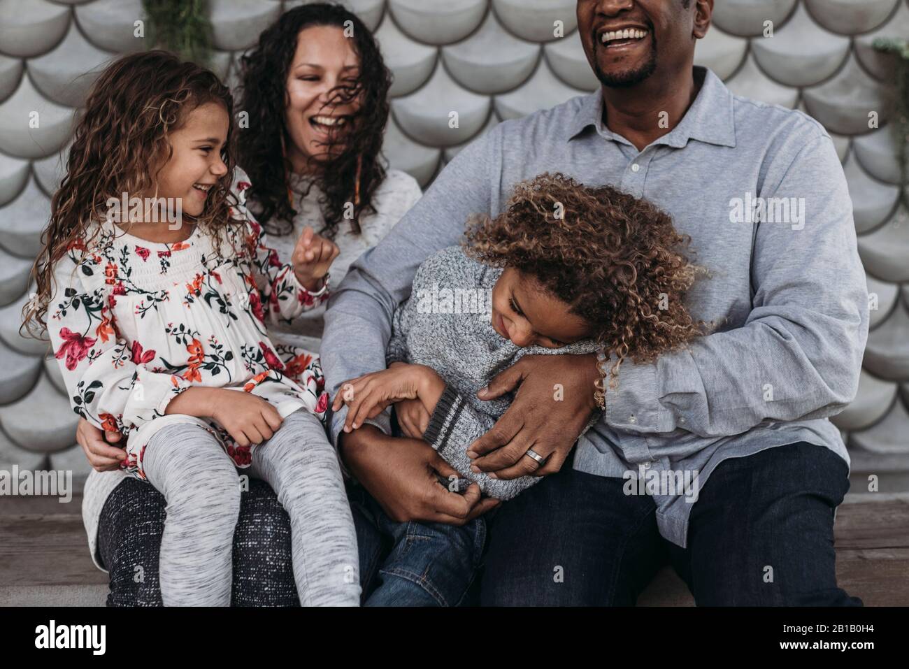 Lifestyle image of happy family tickling each other and laughing while ...