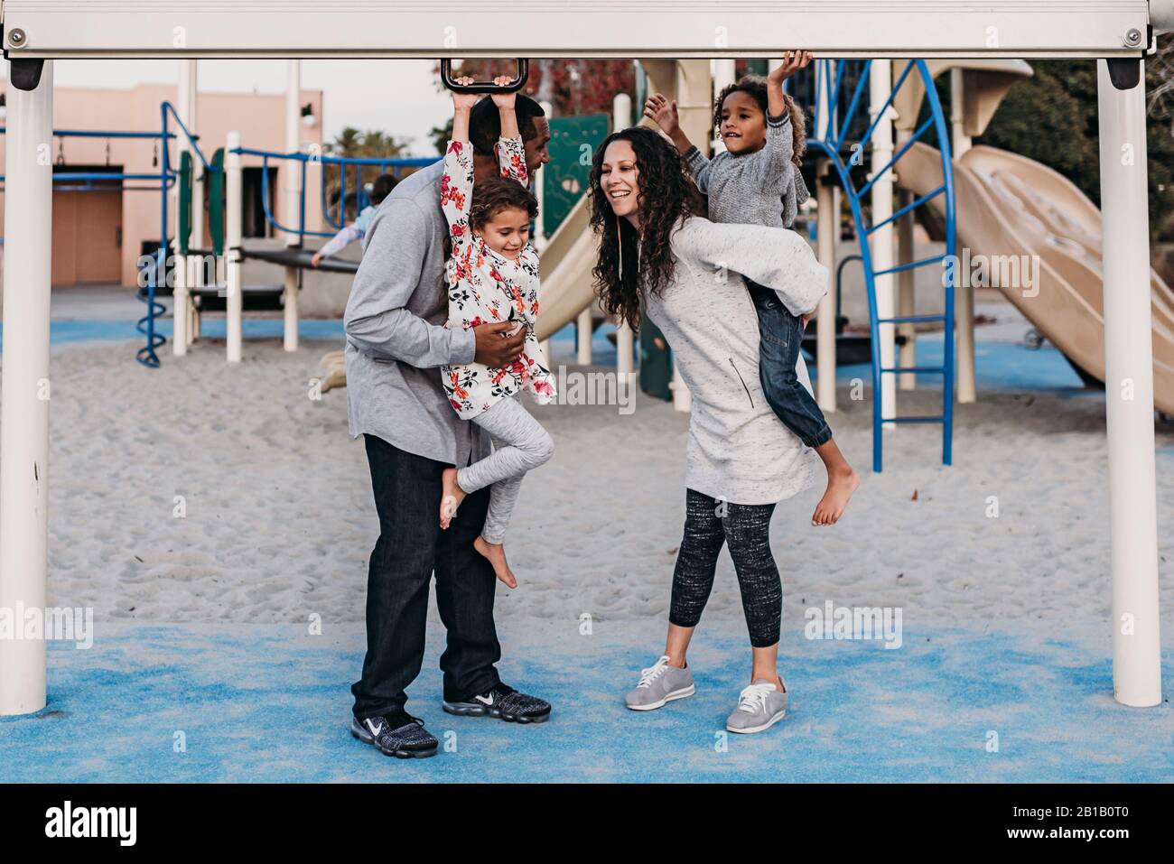 Happy family playing outside at park playground at dusk Stock Photo - Alamy