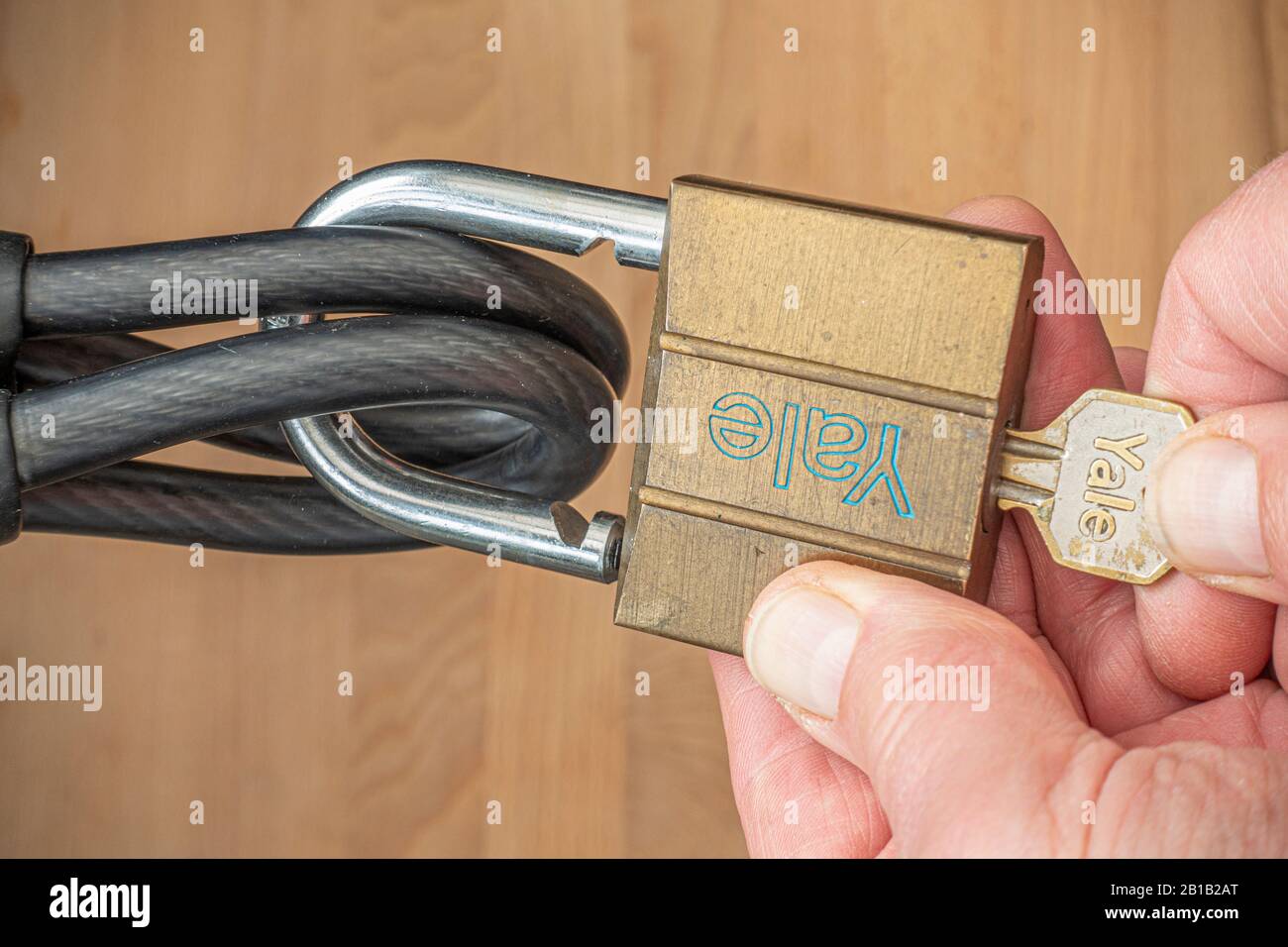A man’s hands unlocking a Yale key operated padlock, through dual ...
