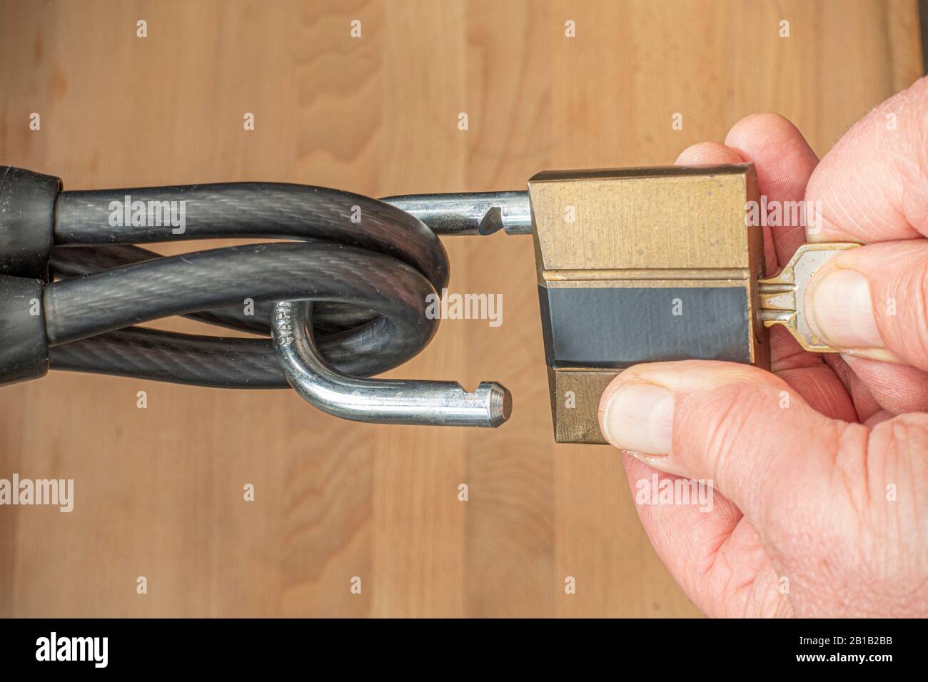 A man’s hands unlocking a key operated padlock, through dual hooped ...