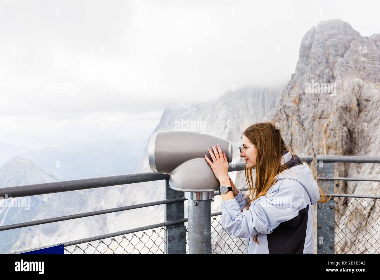 young women looks at mountain views in binoculars from observation ...