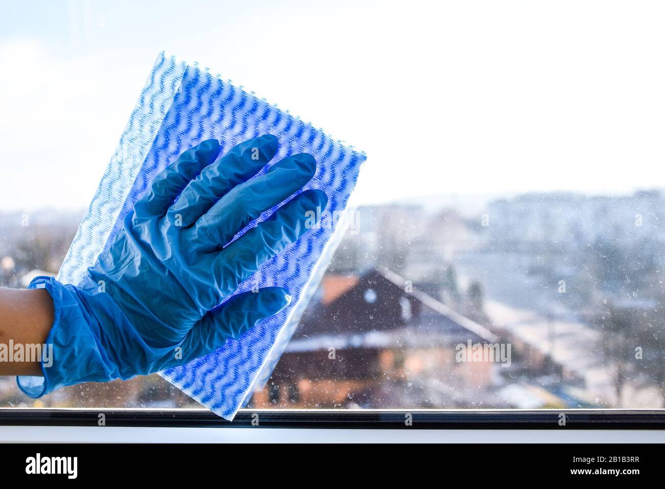 Employee hand in rubber protective glove with micro fiber cloth wiping ...