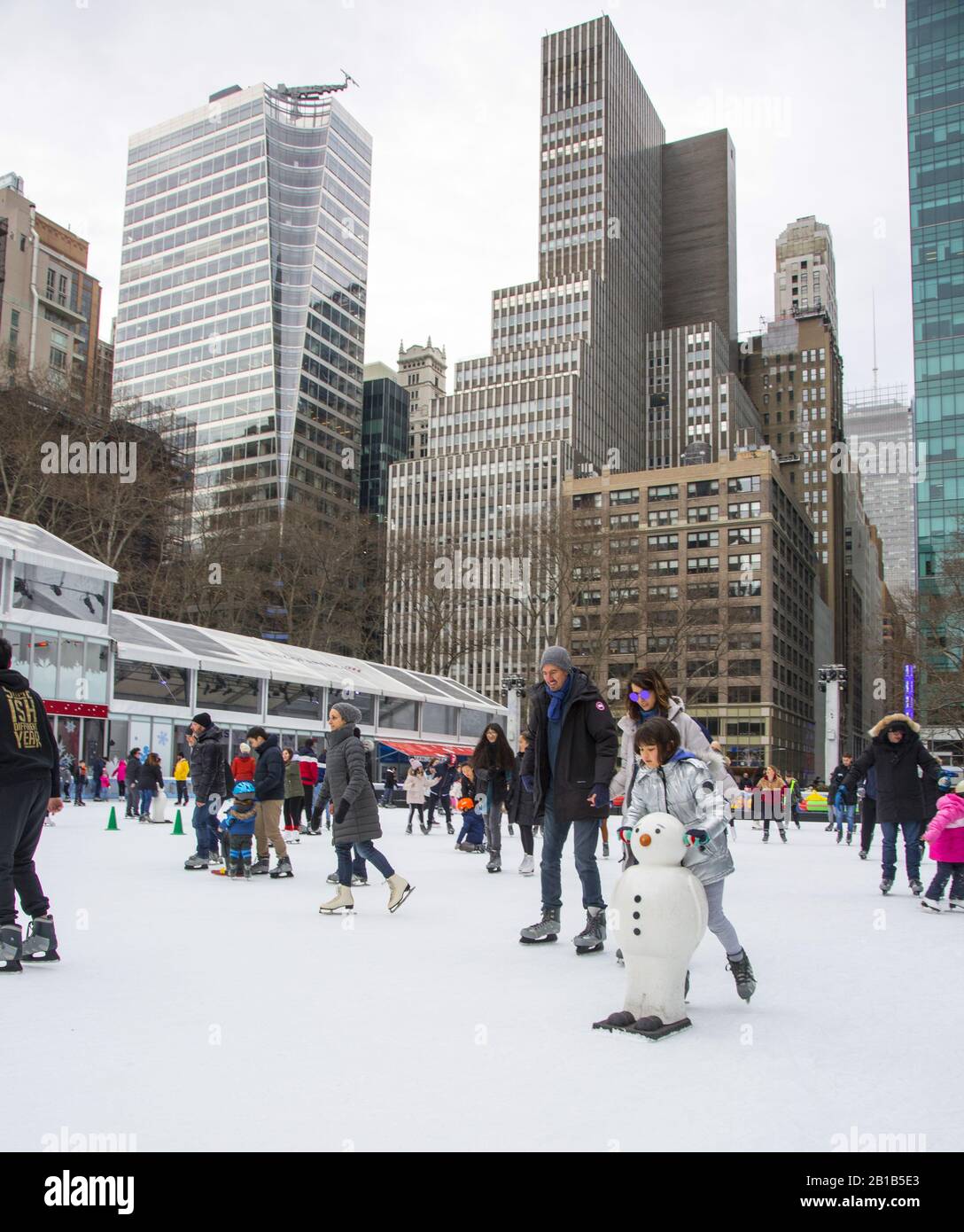 People enjoy ice skating in Bryant Park with the tall buildings of ...