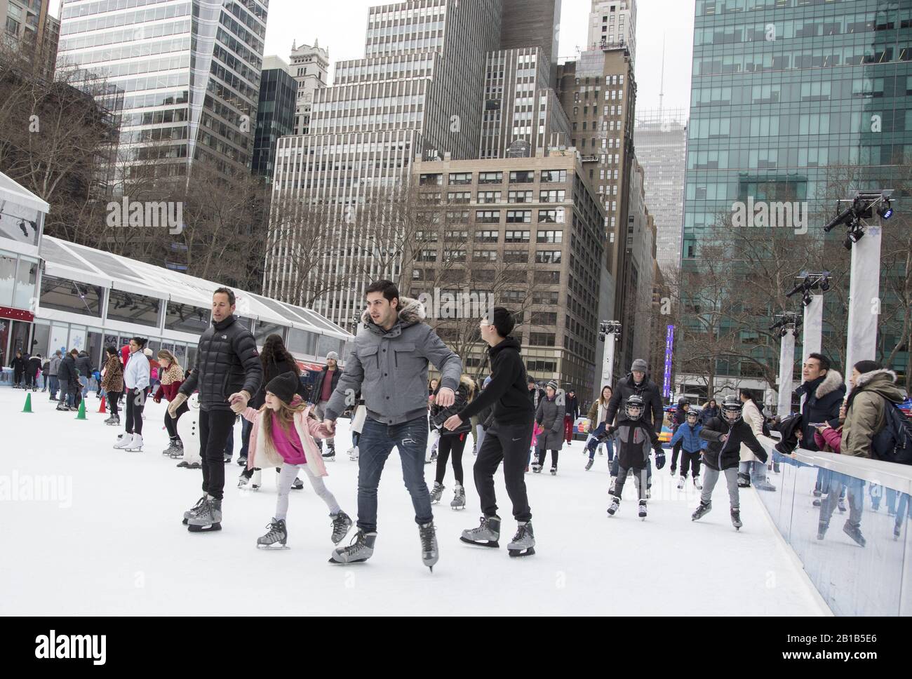 People enjoy ice skating in Bryant Park with the tall buildings of ...