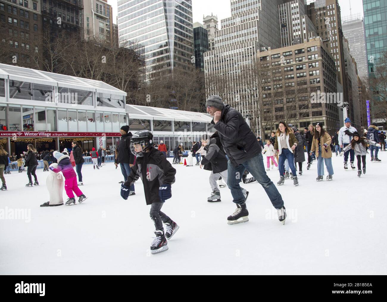 People enjoy ice skating in Bryant Park with the tall buildings of ...