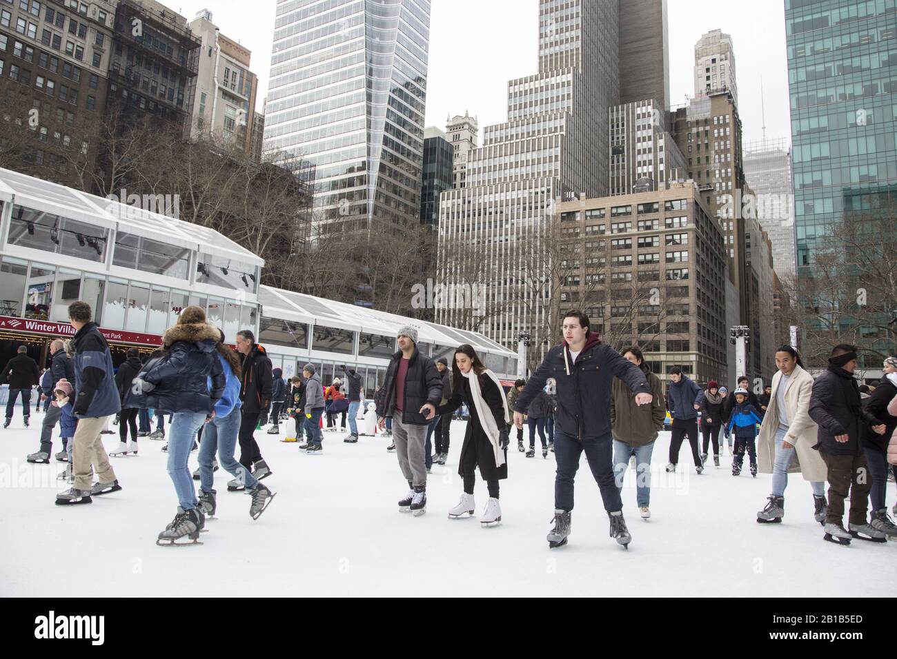 People enjoy ice skating in Bryant Park with the tall buildings of ...