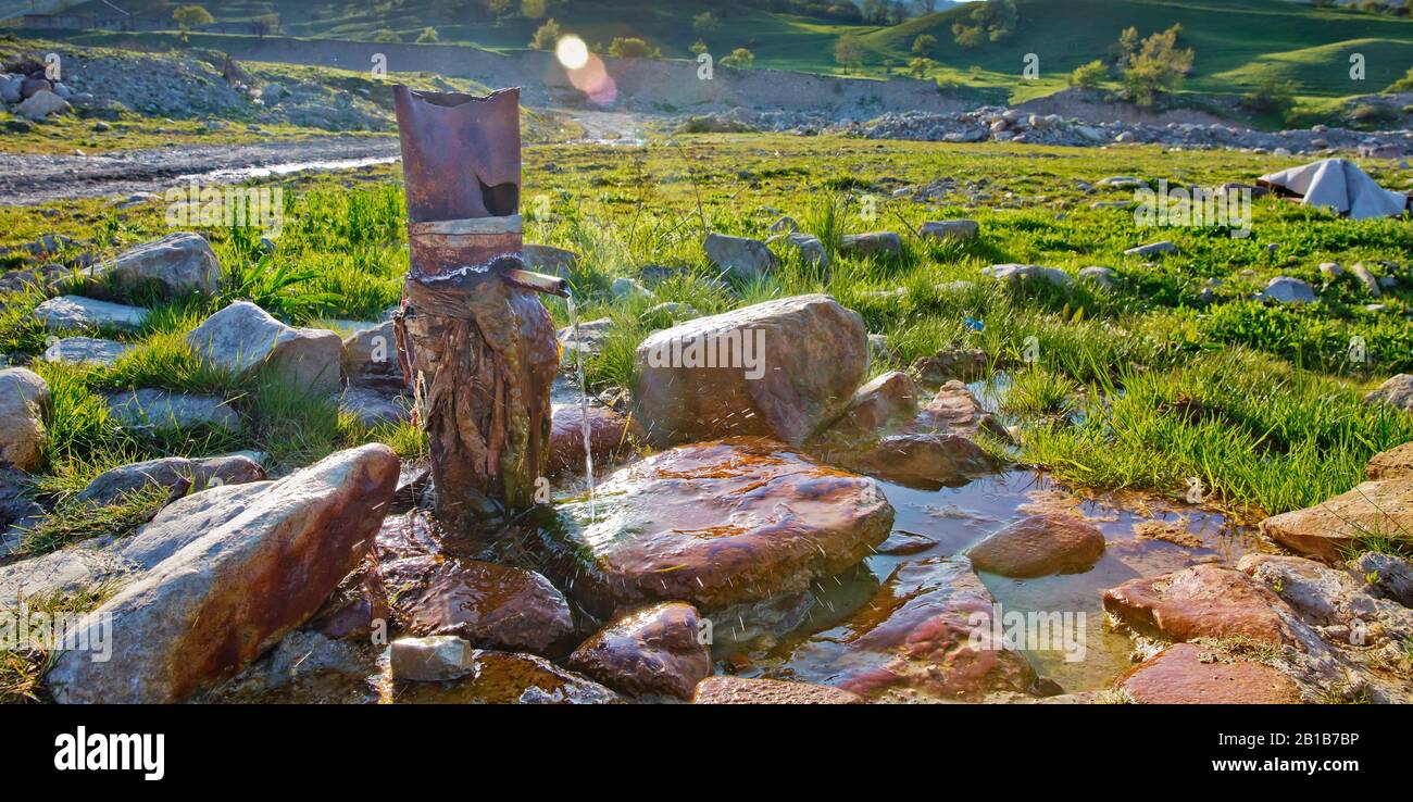 iron pipe flowing clean drinking water . spring water from the ground ...