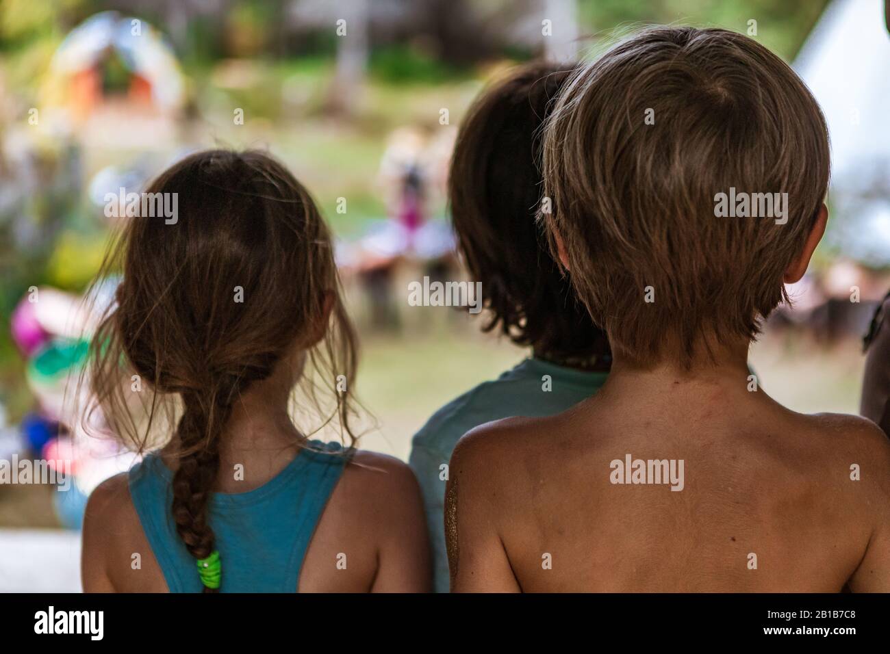 Three innocent children are seen from behind in soft focus during a ...