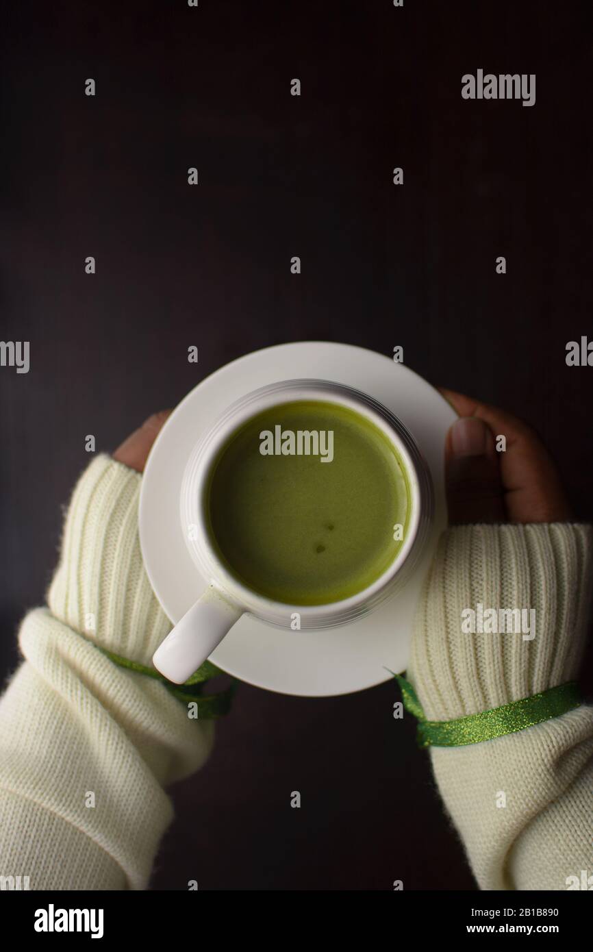 Female hands holding a mug of green matcha tea, matcha latte in white ...