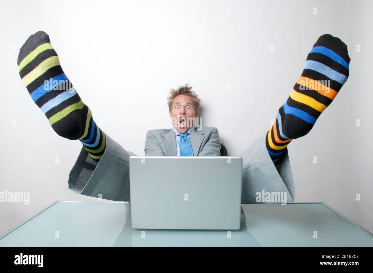 Shocked businessman sitting in front of his laptop computer looking at ...