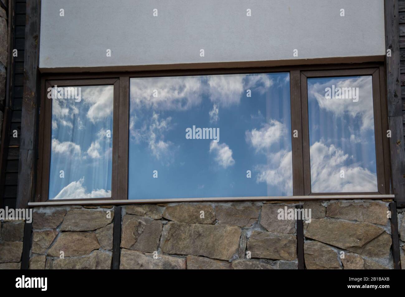 Beautiful white clouds and blue sky reflecting in the windows of a ...