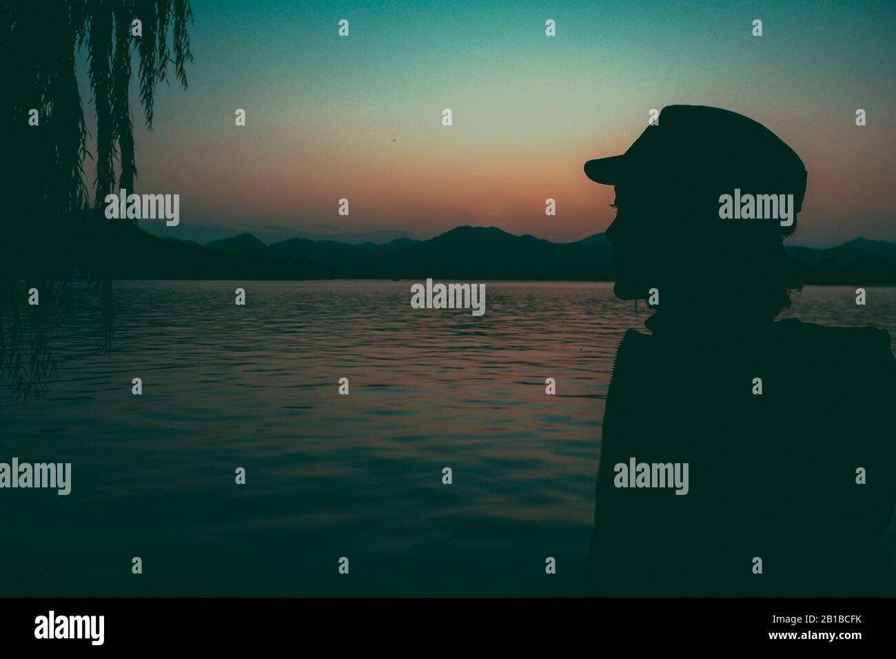 Dusk Woman Lake Silhouette against Orange Sky mountains background ...