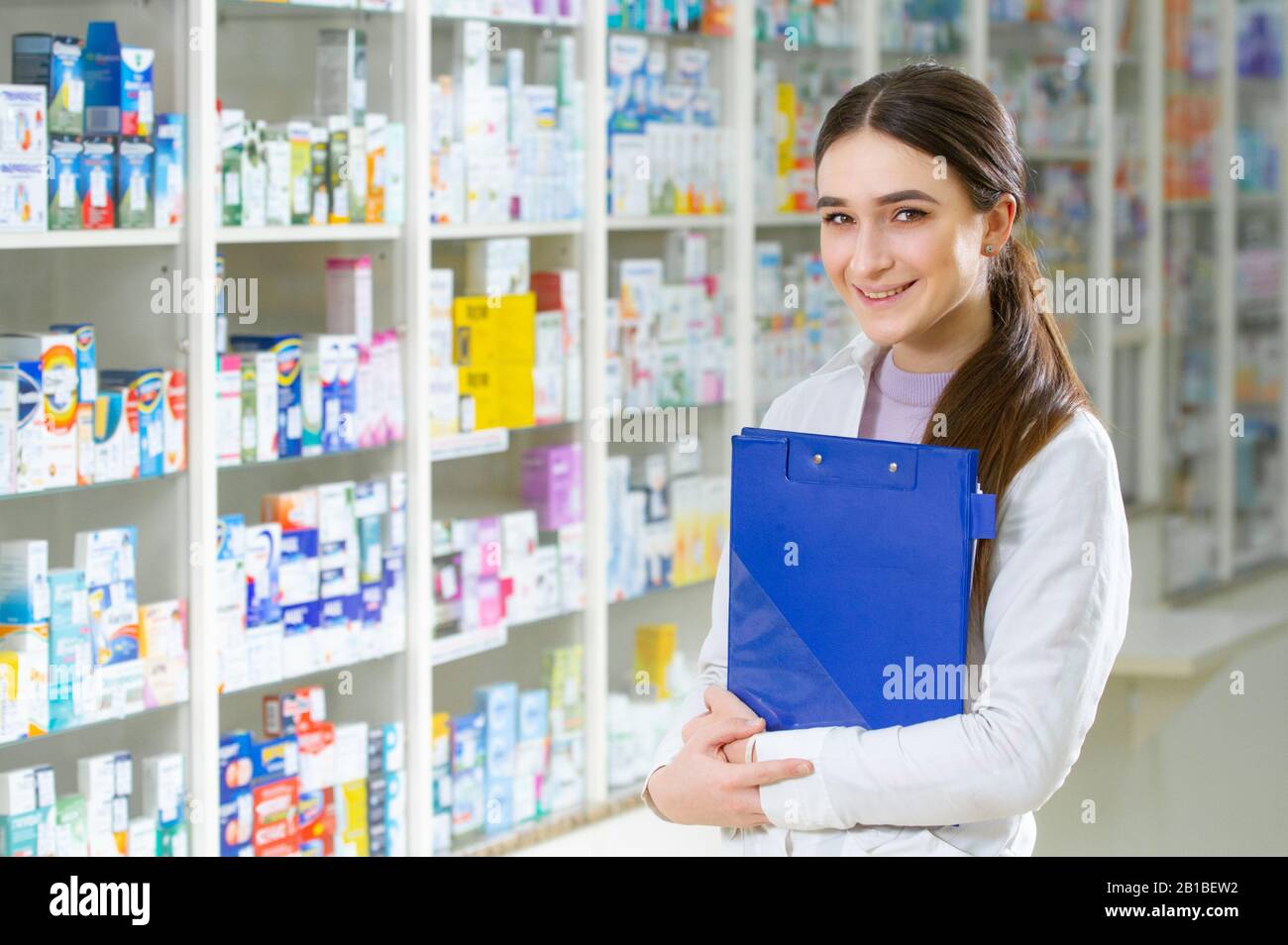 Pharmacist the girl is standing near the pharmacy shelves with ...