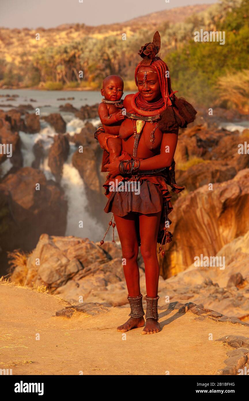Himba woman sporting his neck full of traditional ornaments and a small ...