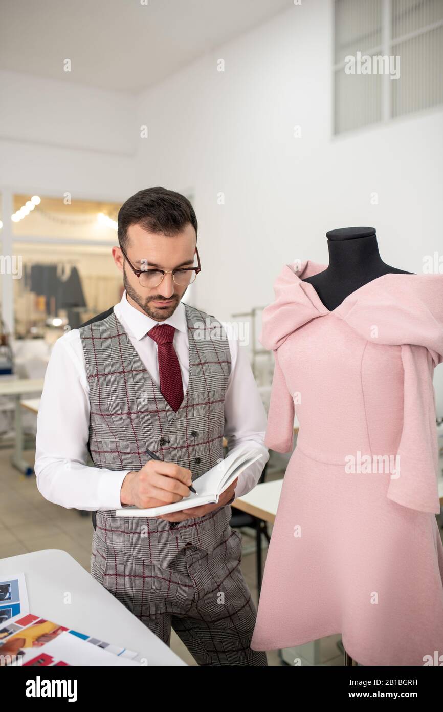 Male tailor standing next to dummy and making notes Stock Photo - Alamy