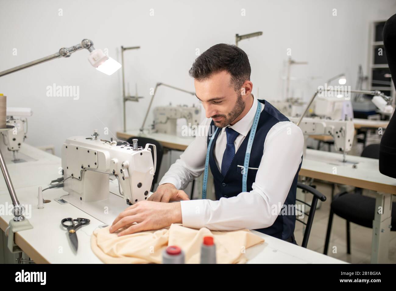 Male tailor sitting at sewing machine and sewing Stock Photo - Alamy