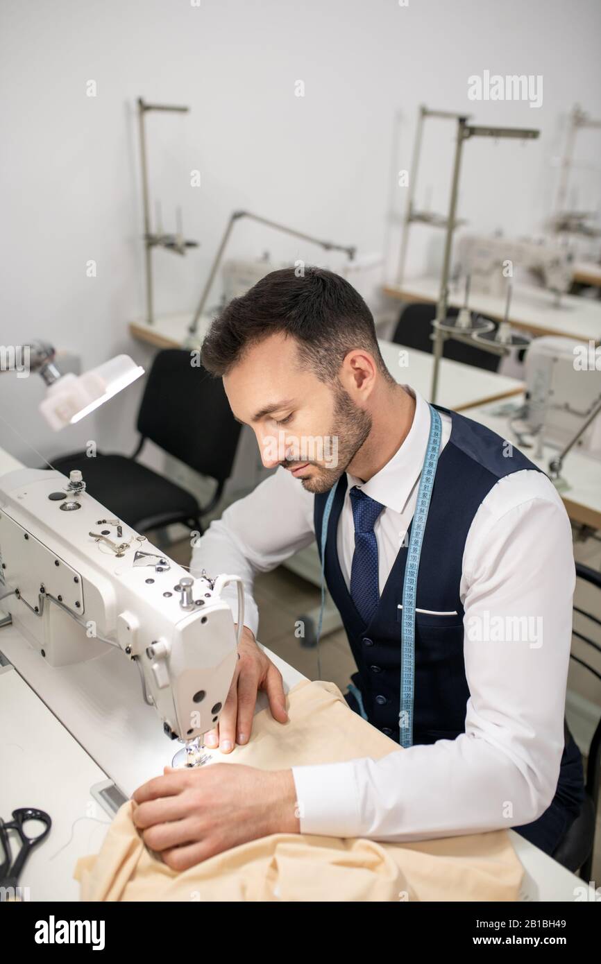 Male tailor sitting at sewing machine and sewing Stock Photo - Alamy