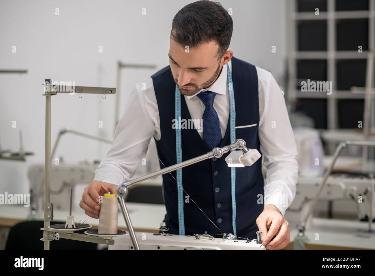Male tailor standing while checking sewing machine Stock Photo - Alamy