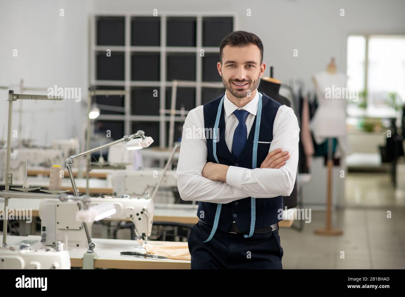Male tailor standing with folded hands, smiling Stock Photo - Alamy