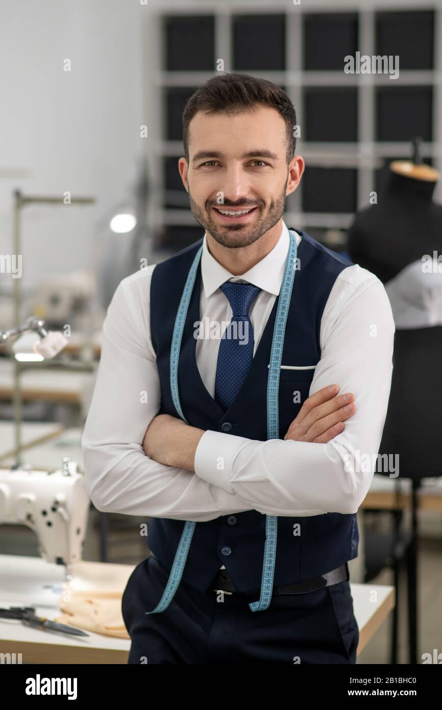 Male tailor standing with folded hands, smiling Stock Photo - Alamy