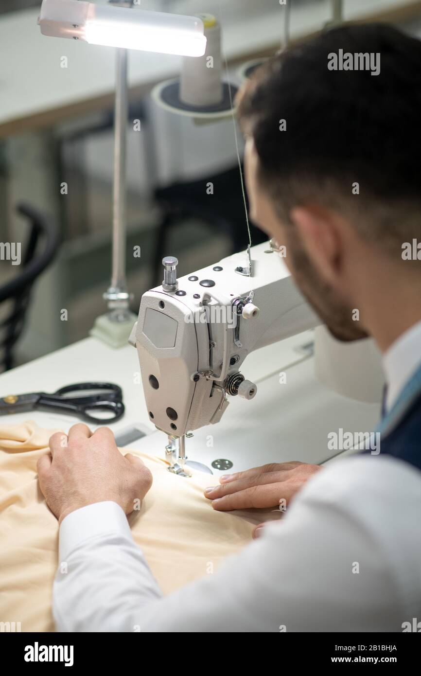 Male fashion designer sitting on sewing machine Stock Photo - Alamy
