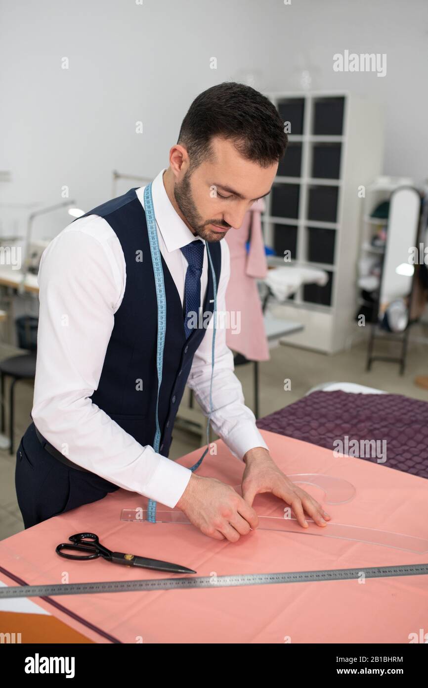 Male tailor outlining pattern on pink cloth Stock Photo - Alamy