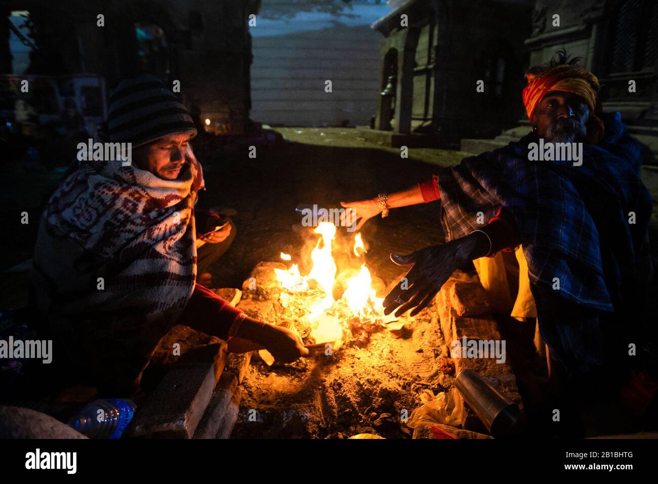 Hindu holy men or Sadhu sits next to a bonfire at the premises of ...